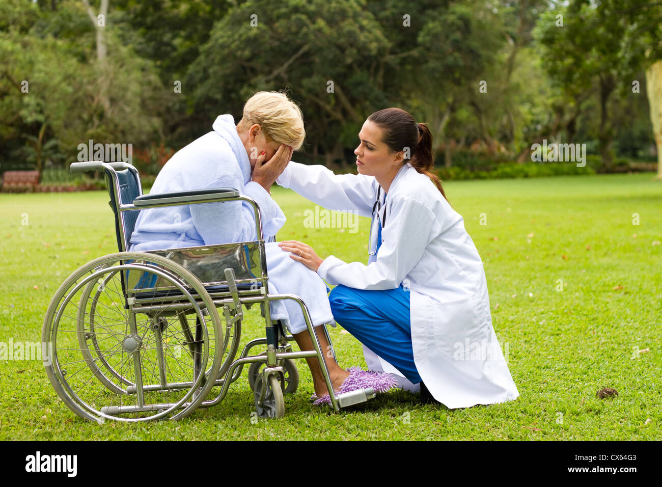 caring young female doctor comforting a lonely disabled senior patient ...