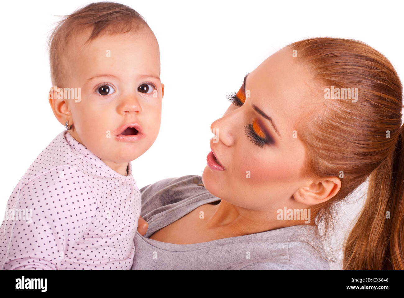 Mother holding amazed baby girl with lipstick isolated on white ...
