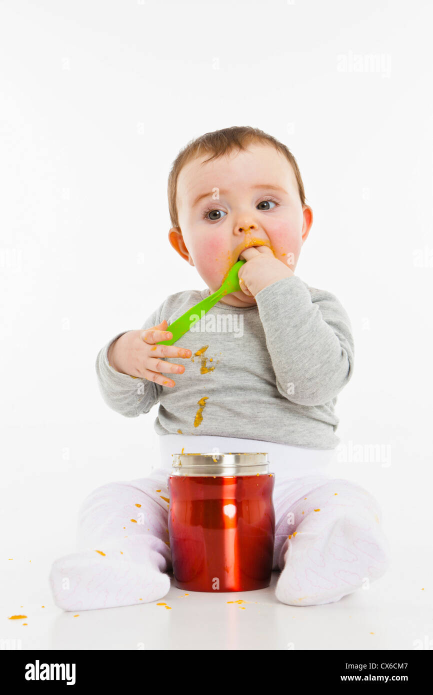 A baby eating food from a container Stock Photo - Alamy