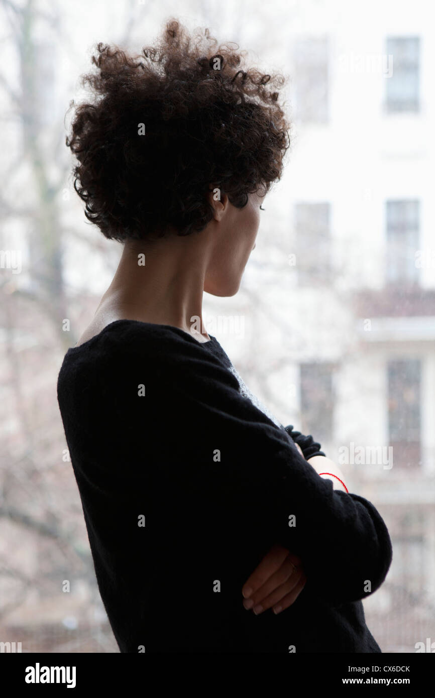 Side view of a woman looking through a window Stock Photo - Alamy