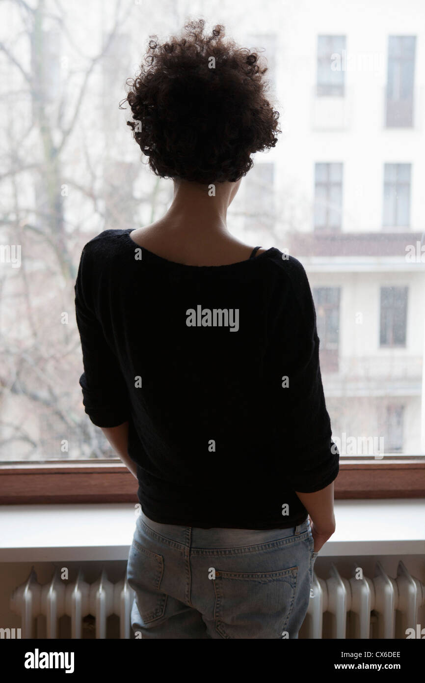Rear view of a woman looking through a window Stock Photo - Alamy