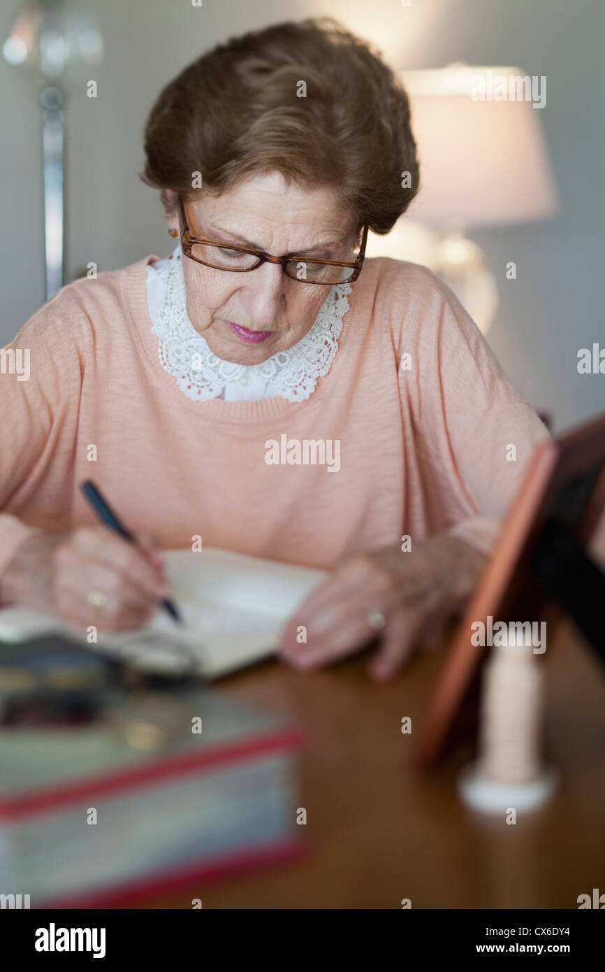 A senior woman writing in a note book Stock Photo - Alamy