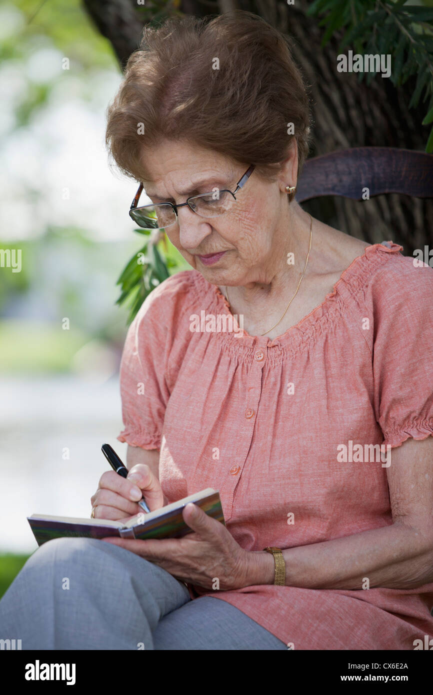 A senior woman writing in a book Stock Photo - Alamy
