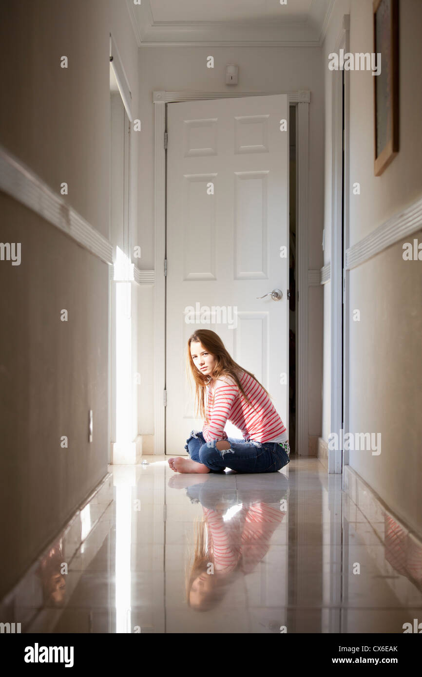 Girl sitting cross-legged in hallway Stock Photo - Alamy