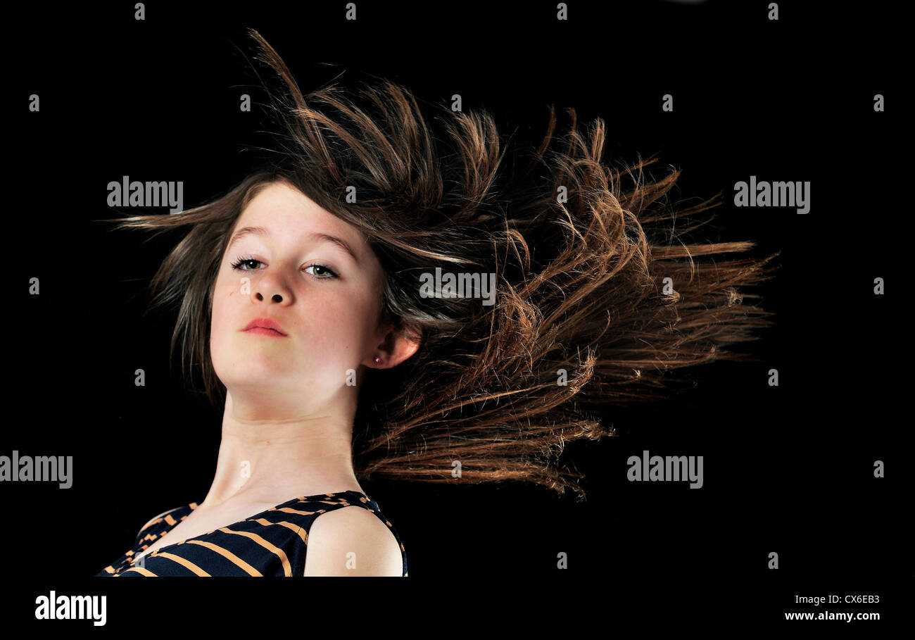 Girl flicking her hair with black background Stock Photo - Alamy