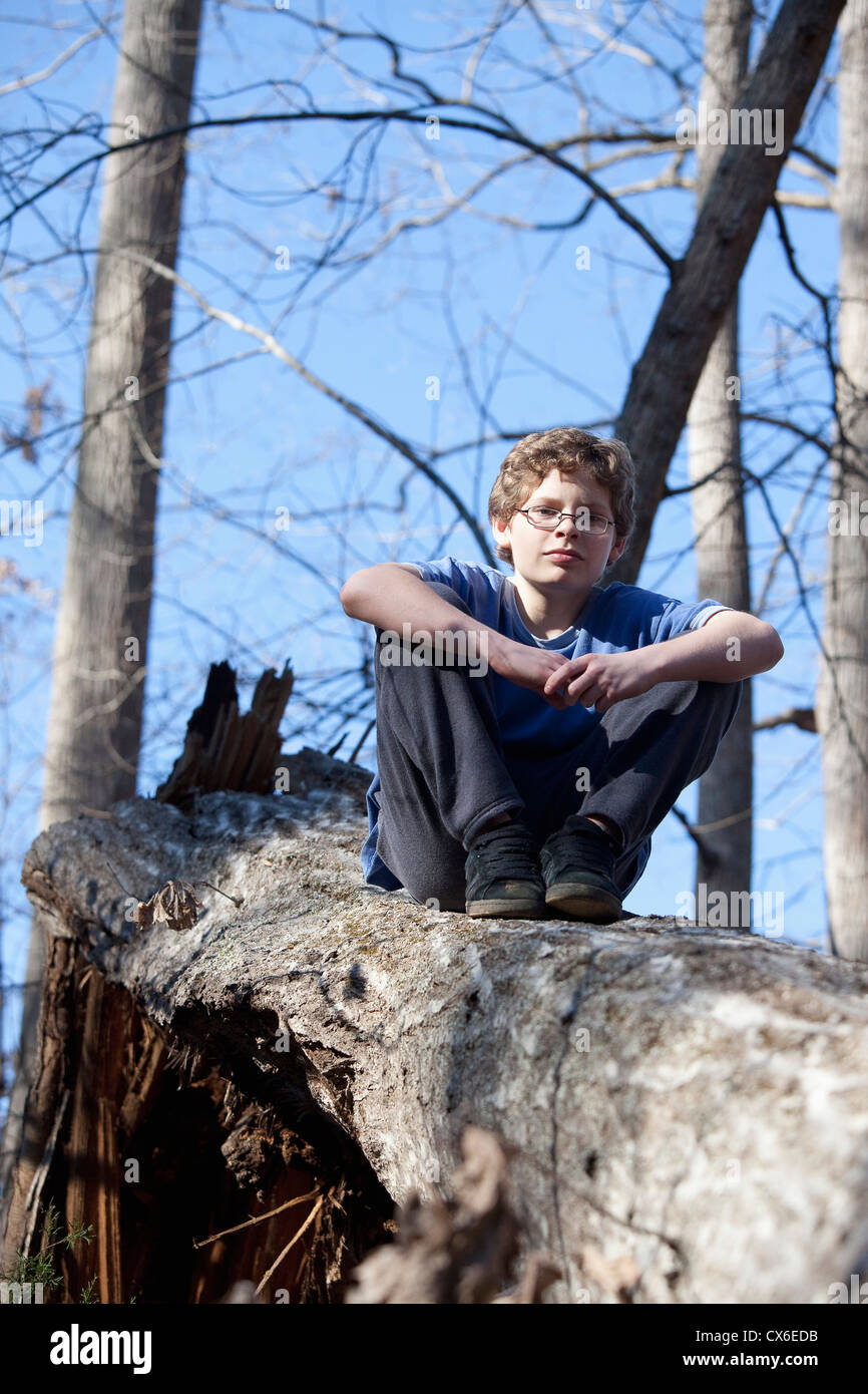 Boy sitting on broken tree trunk Stock Photo - Alamy