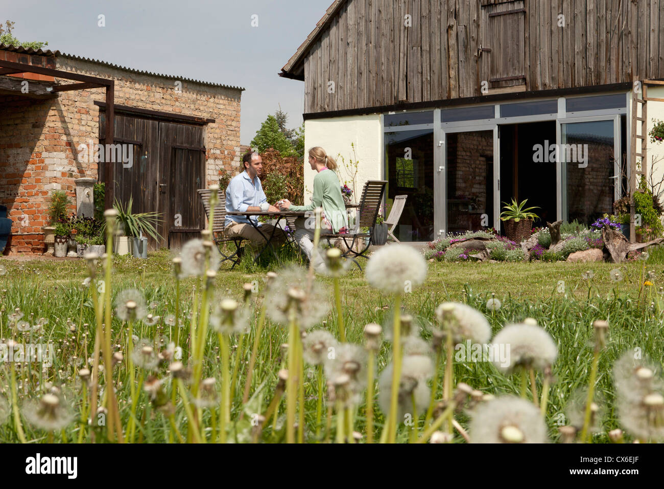A couple sitting at a table in their backyard talking Stock Photo - Alamy