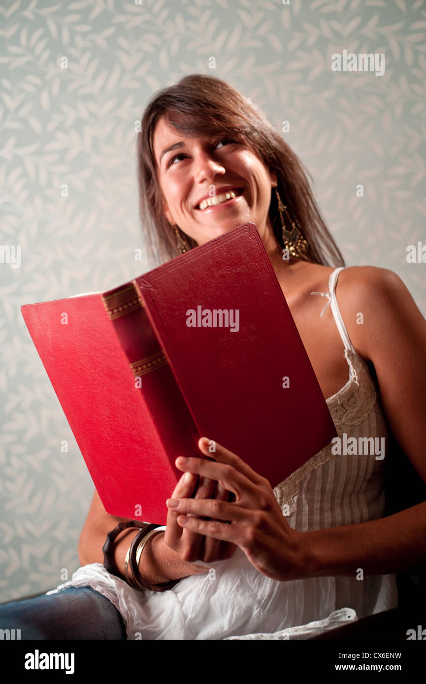 Woman reading and smiling with red book Stock Photo - Alamy