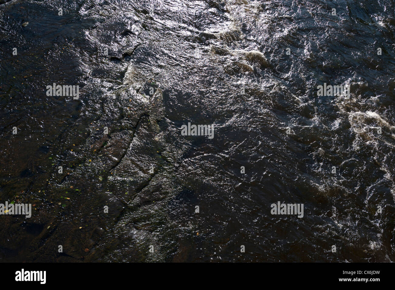 Flowing river water with sparkling sunshine glinting off the fast ...