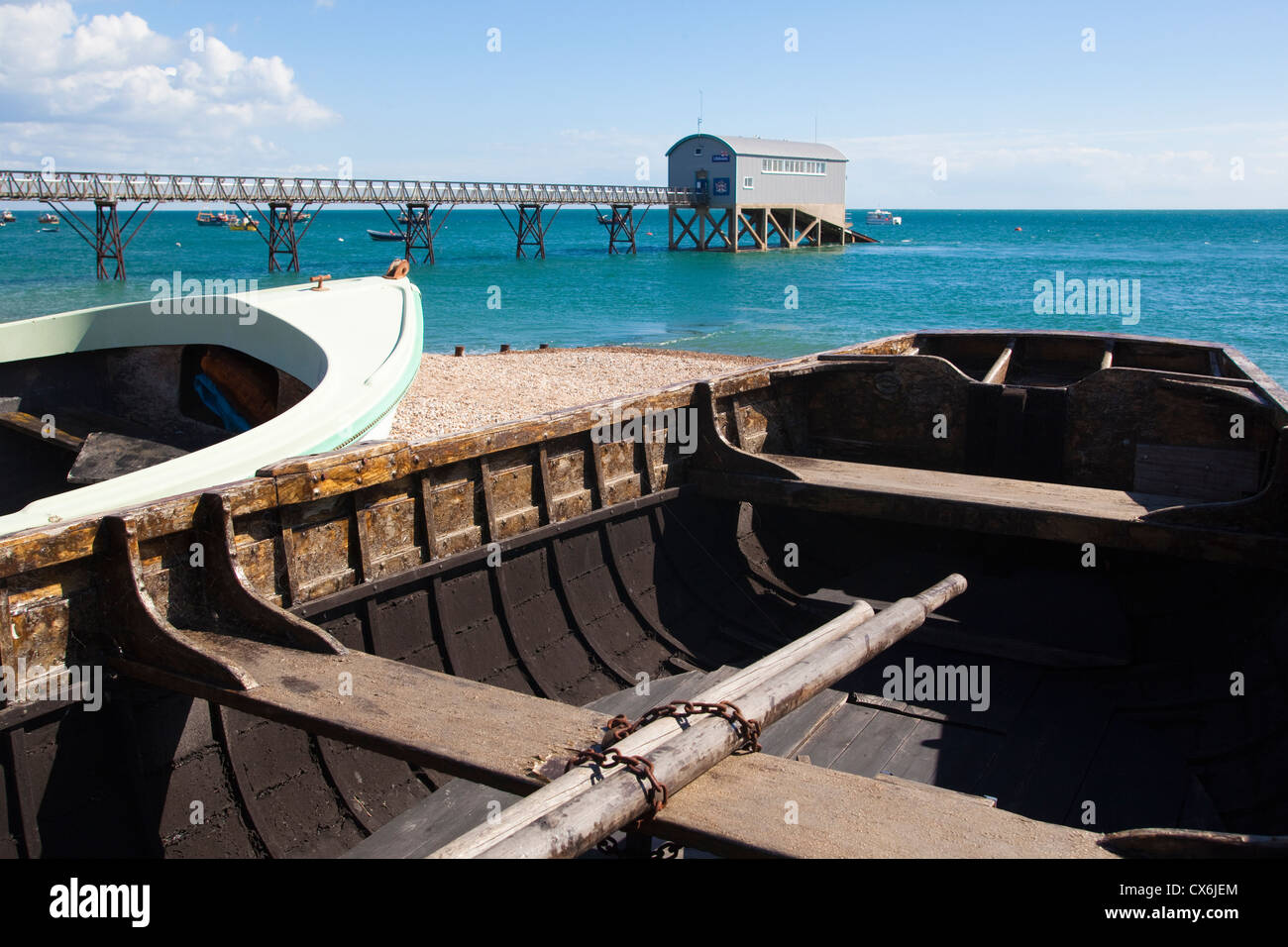Wooden rowing boat on Selsey beach with lifeboat station in the ...