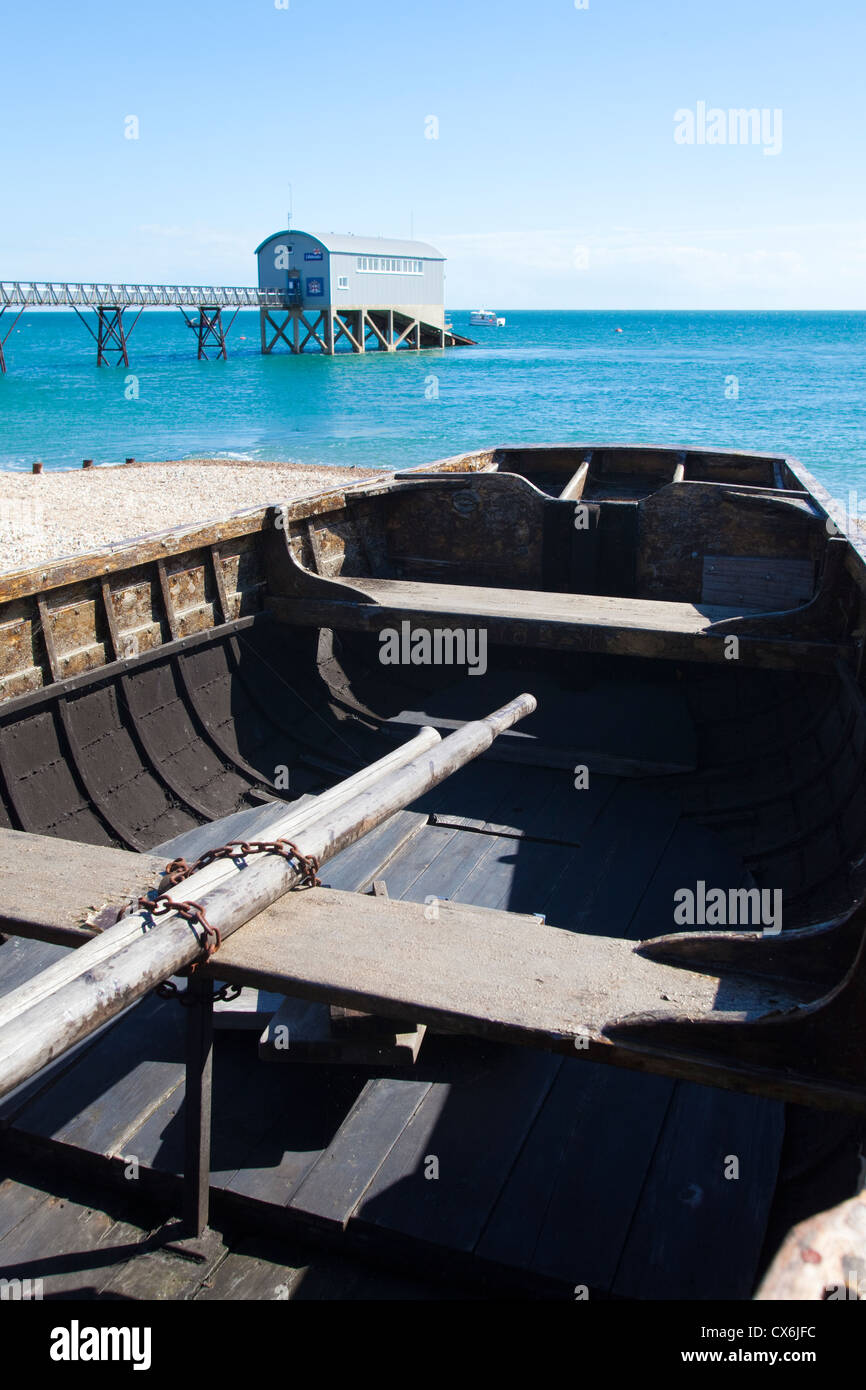 Wooden rowing boat on Selsey beach with lifeboat station in the ...