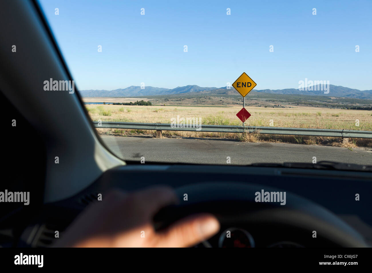 View through a car windshield of an END road sign and mountain ranges ...