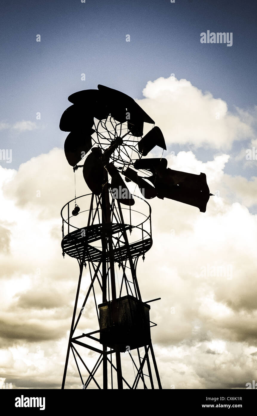 Old Farm Windmill for Pumping Water with Spinning Blades against cloudy ...