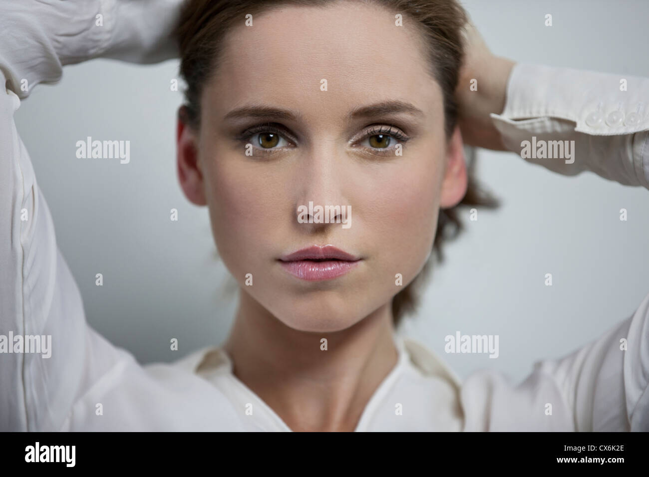 A young woman holding her hair back from her face Stock Photo - Alamy