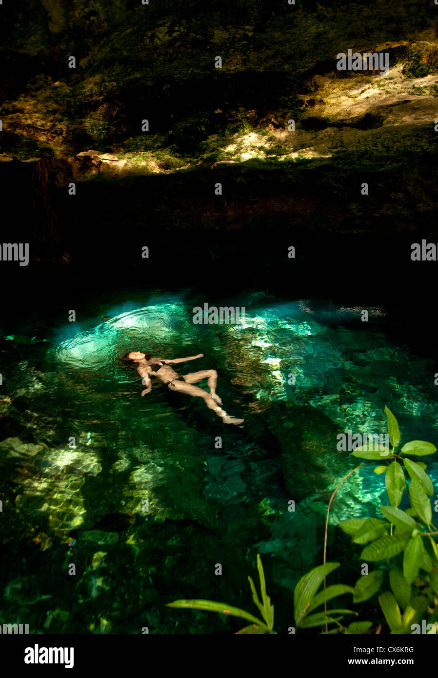 Woman swimming in the azure blue water of the Chac Mool Cenote cave ...