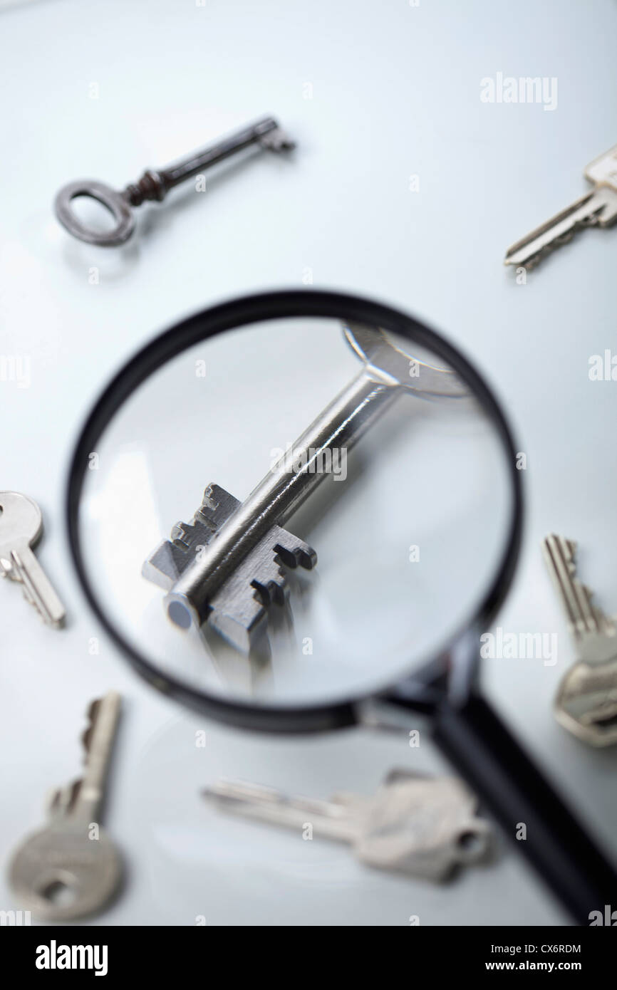 A key lying amongst many being magnified by a magnifying glass Stock ...
