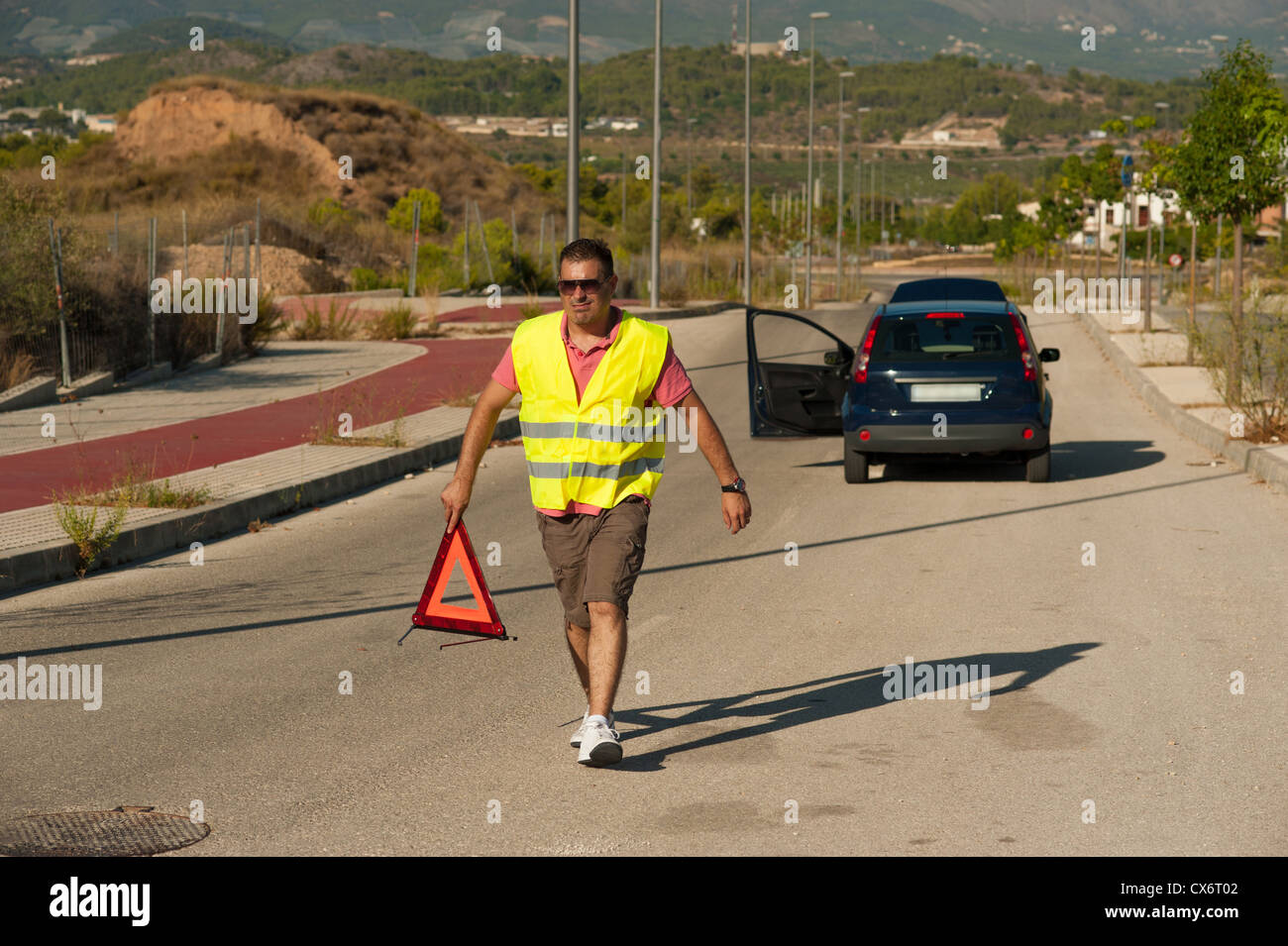 Guy carrying a triangle to warn of his breakdown Stock Photo - Alamy