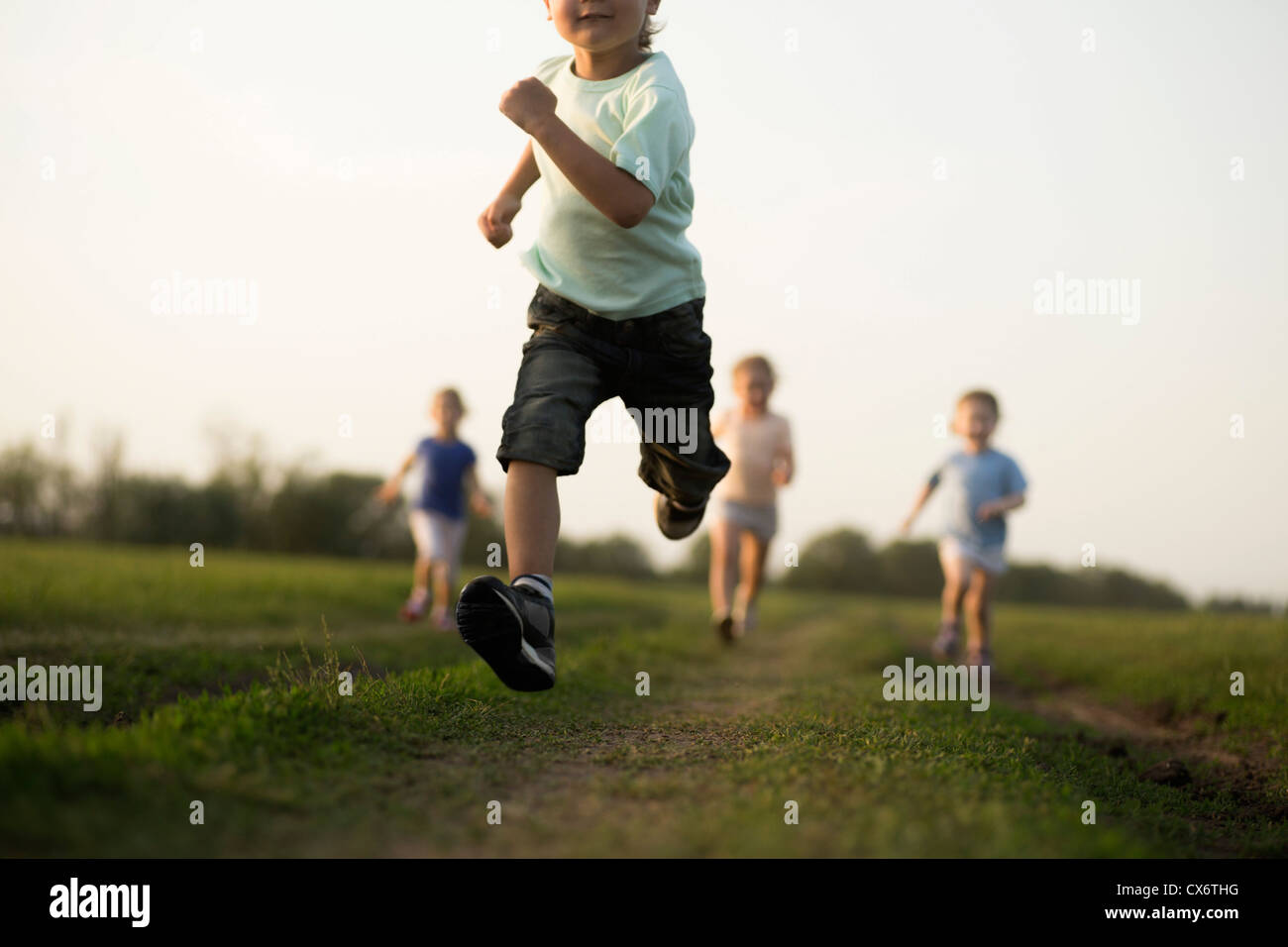 Low view of a boy running in a field with other children behind Stock ...