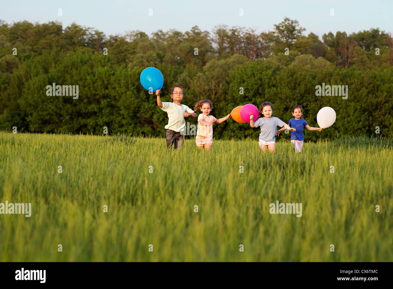 Children running in a field with balloons Stock Photo - Alamy