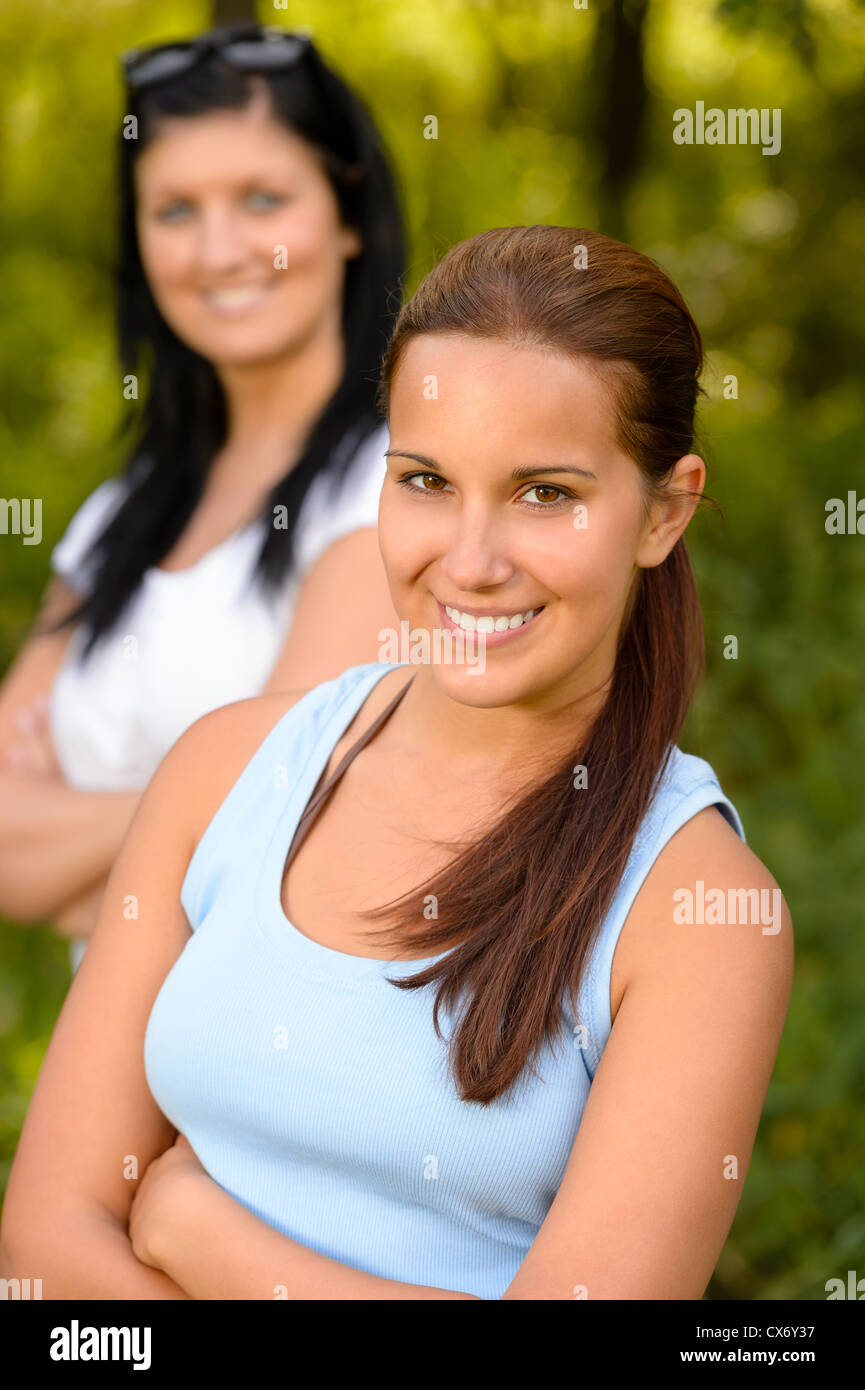 Teen girl smiling with mother in background relaxing outdoors youth ...