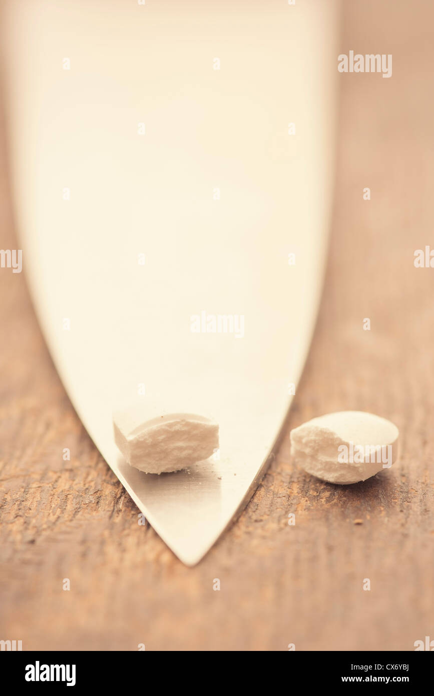 Medical capsule divided into two halves by large knife Stock Photo - Alamy