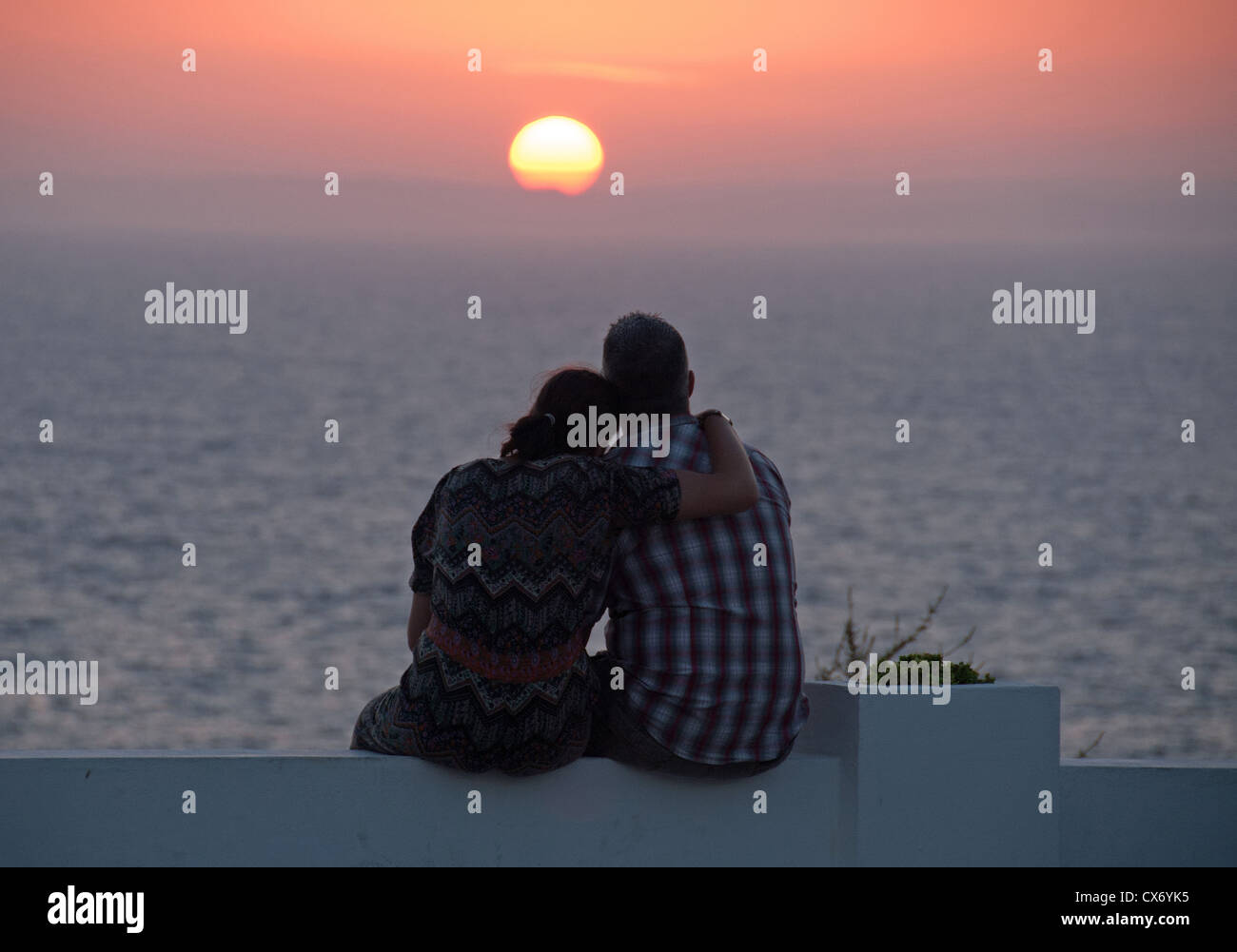 A couple watching the sun setting over the sea. 2012 Stock Photo - Alamy