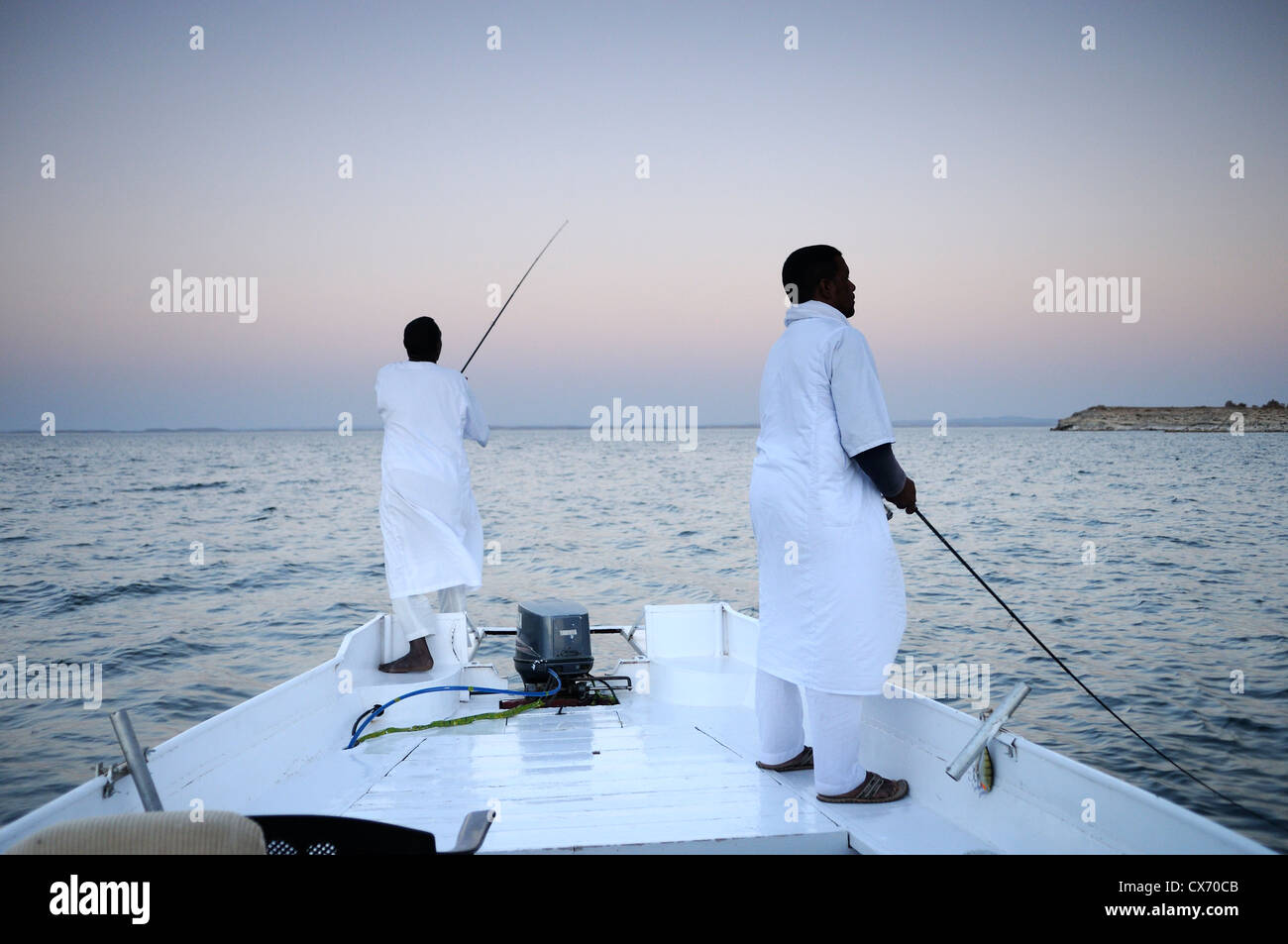 Two Men Fishing off the Back of a Boat Stock Photo - Alamy