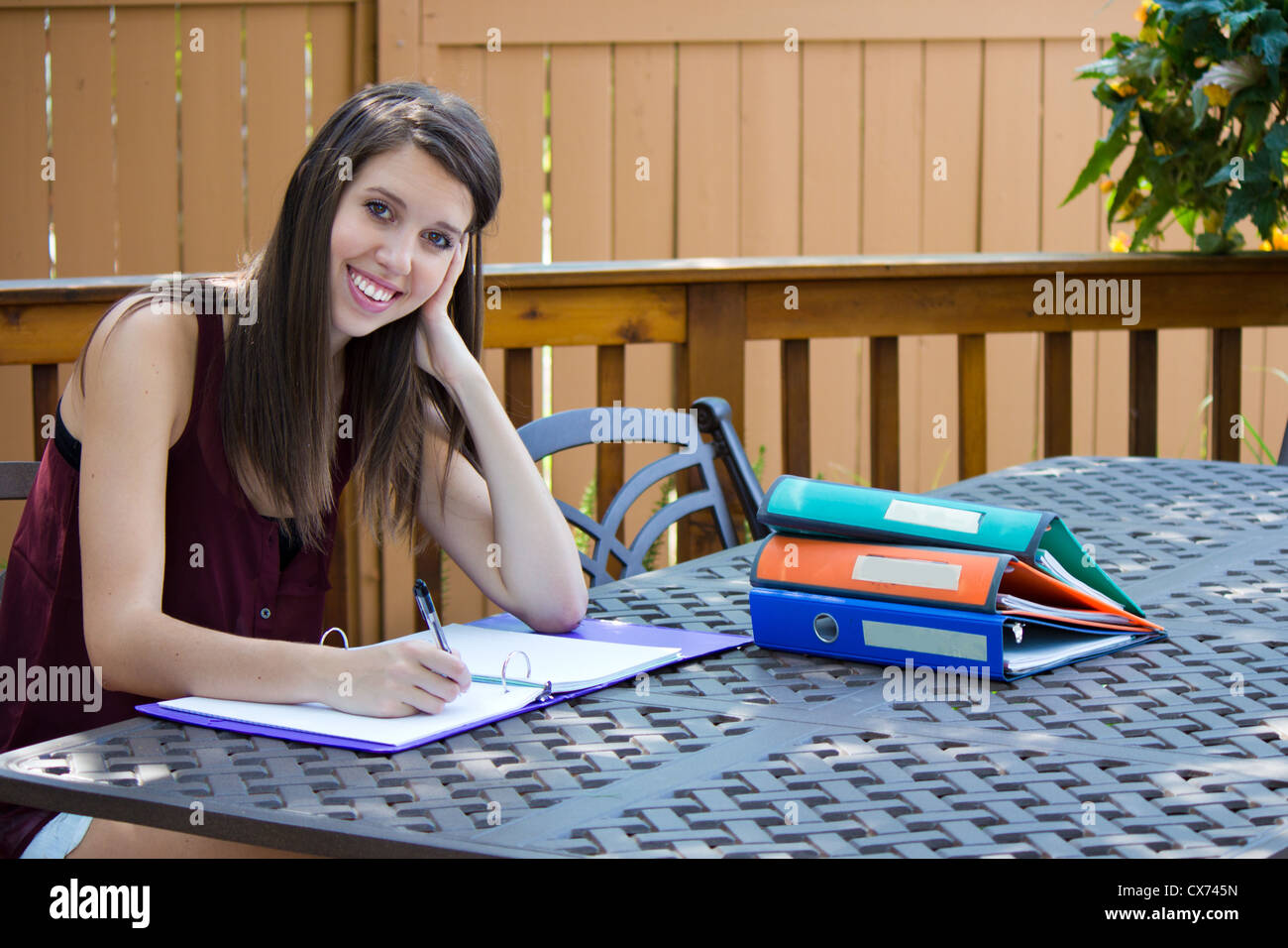 A pretty girl doing homework on a patio outside Stock Photo - Alamy