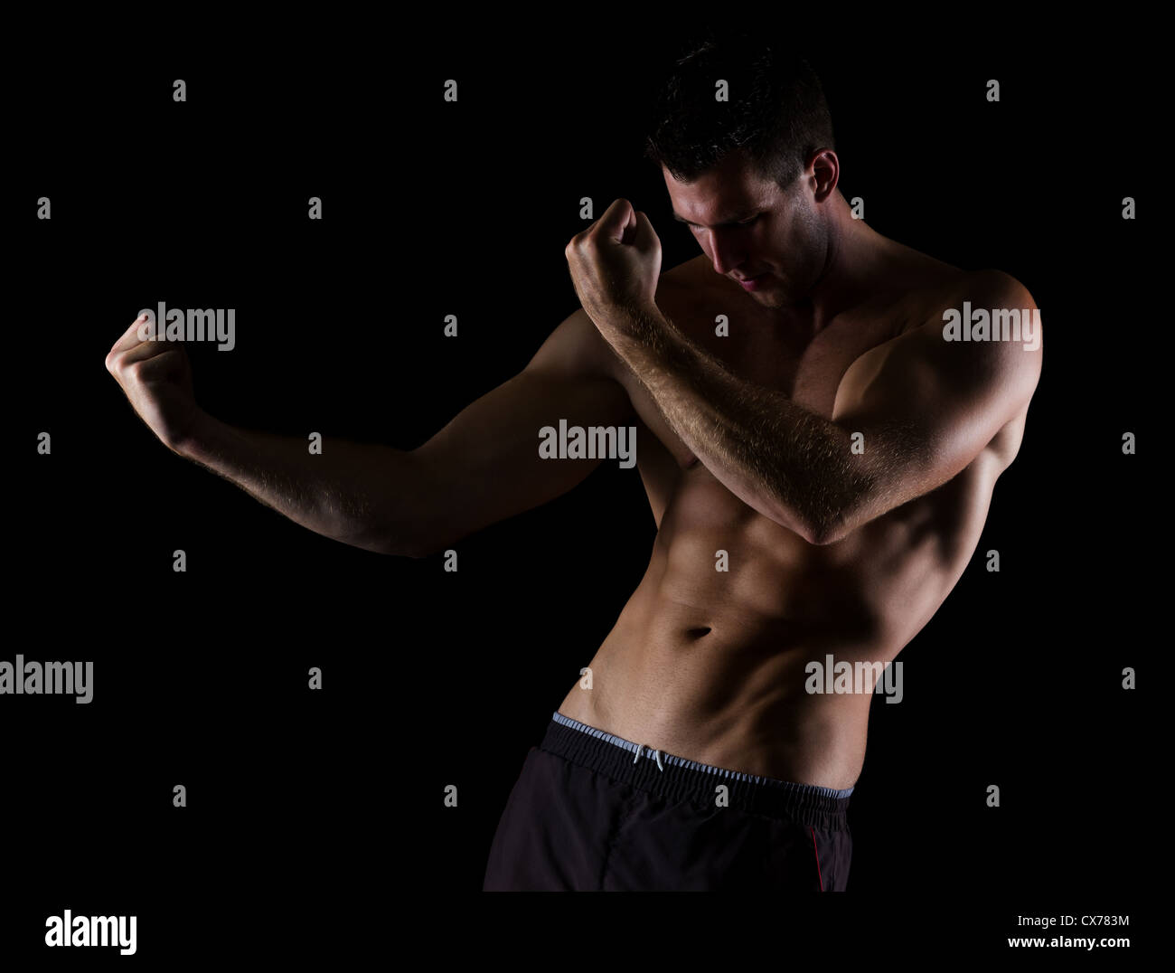 Muscular man in attack pose on black Stock Photo - Alamy