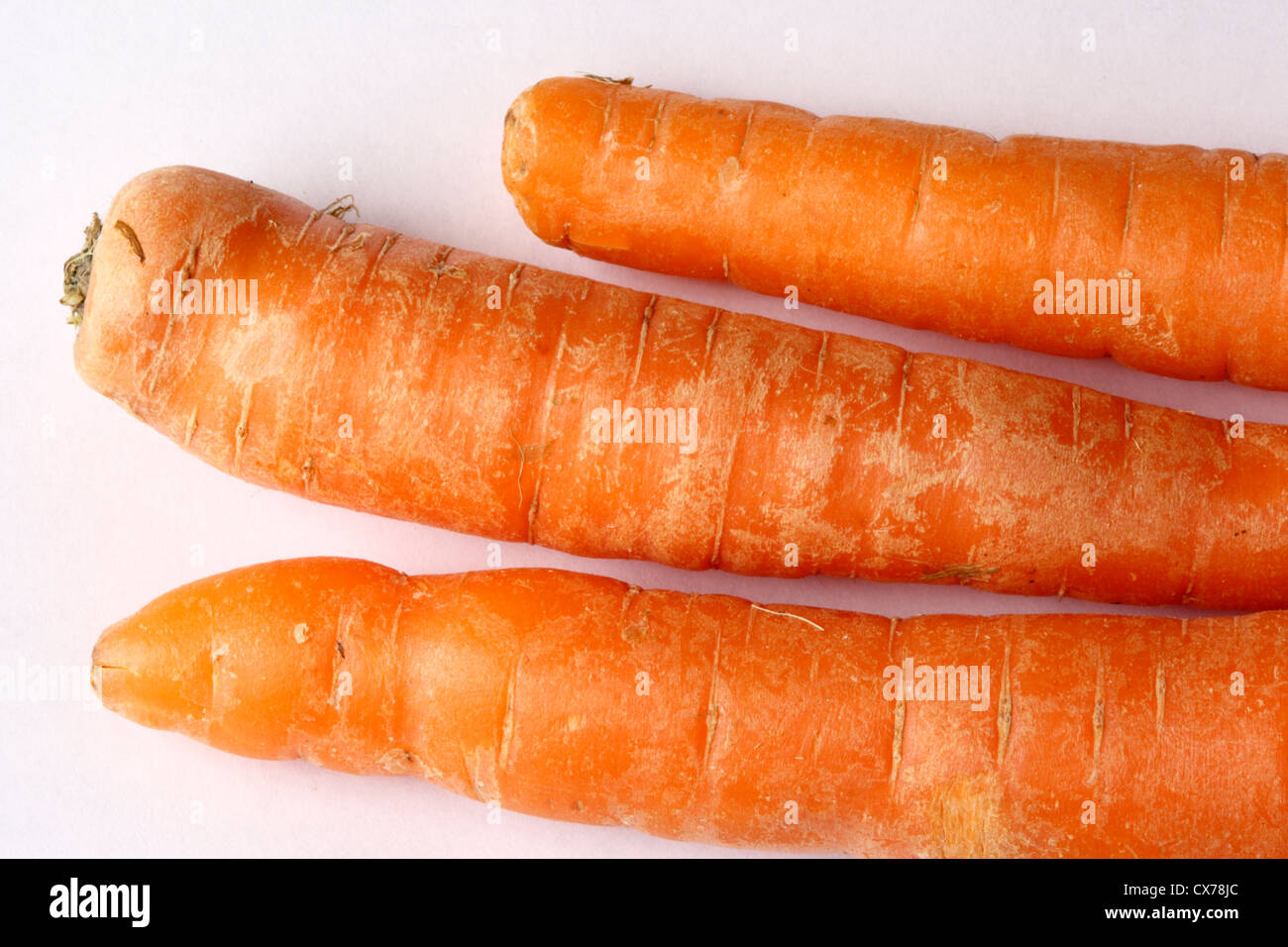 Three carrots on white background Stock Photo - Alamy