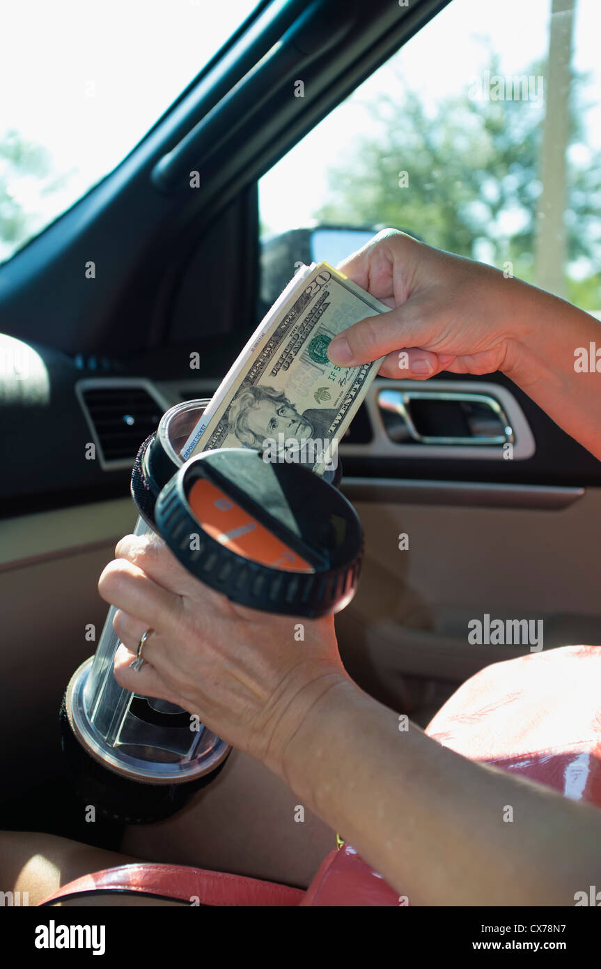 Woman putting money and deposit slips into pneumatic air tube container ...