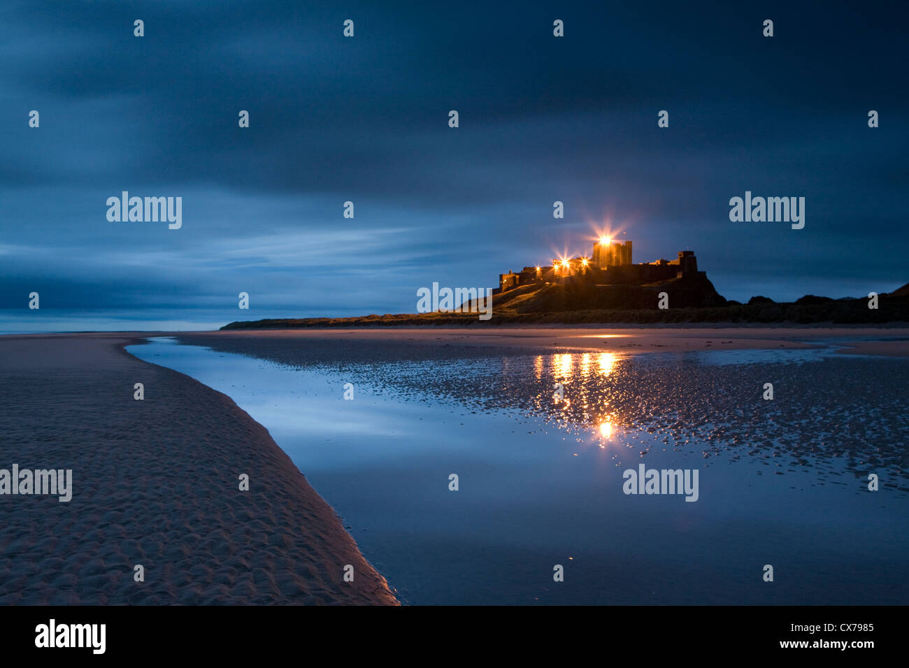 Bamburgh Castle on the Northumberland coast is reflected in water on ...
