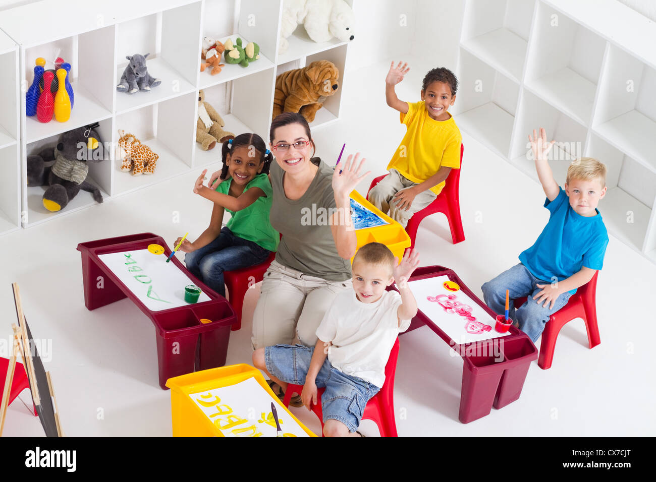 overhead view of group of preschool teacher and students in classroom ...