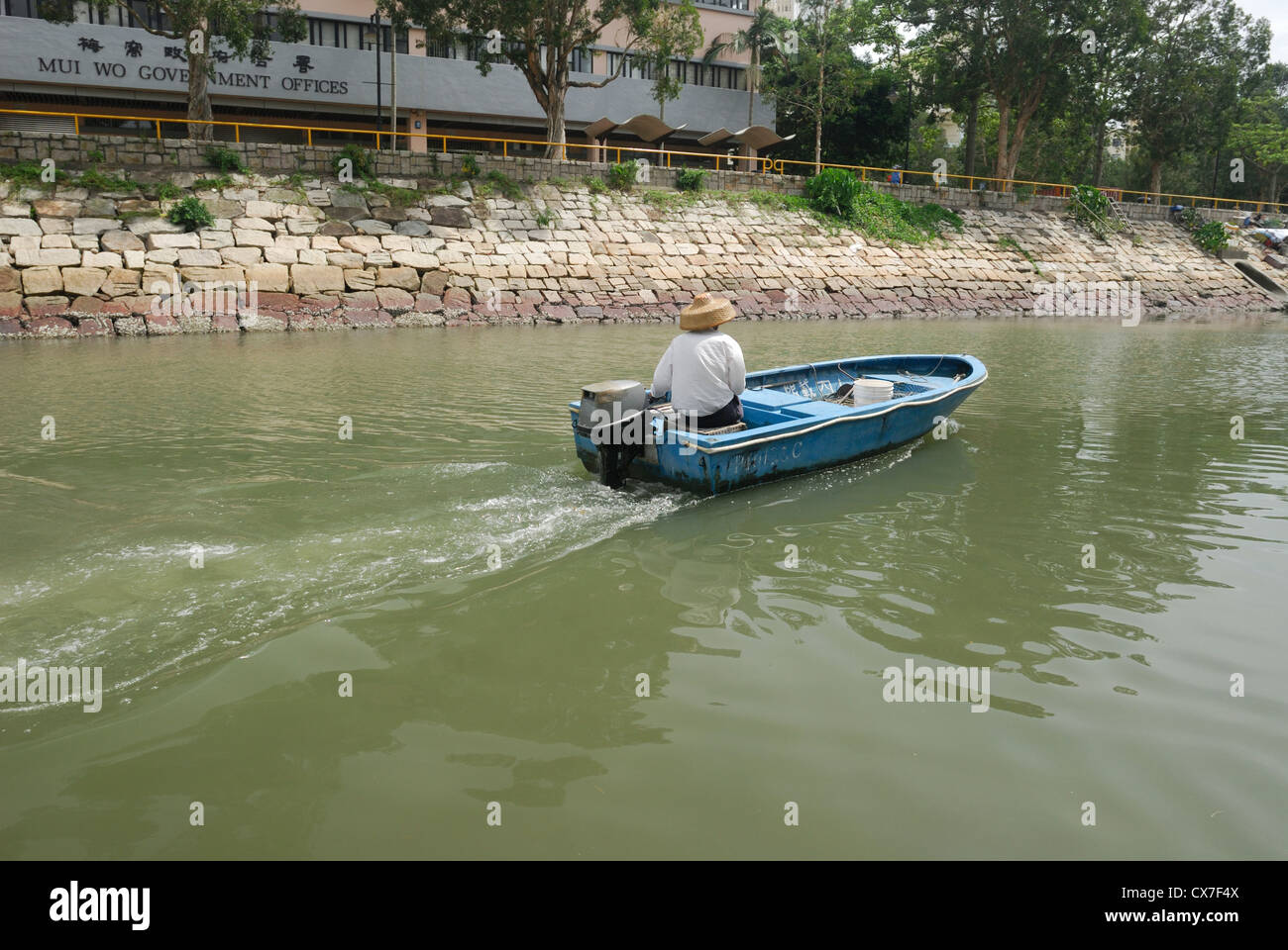Fisherman travelling up the Silvermine River in his small boat, Mui Wo ...