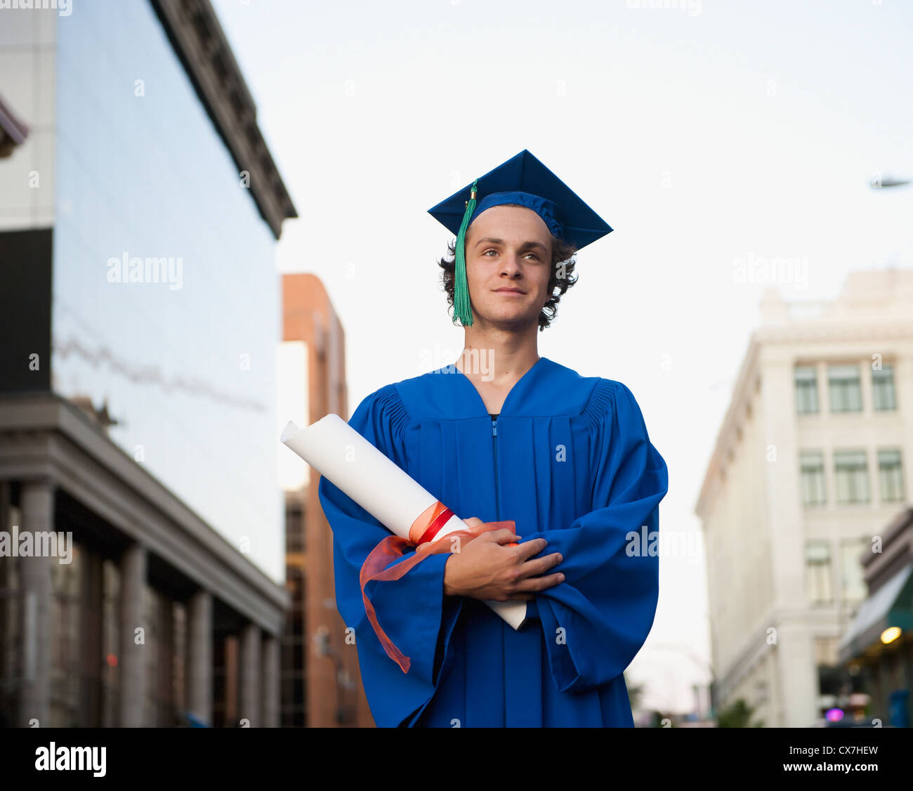 A Graduate In Cap And Gown Holding His Degree On An Urban Street ...