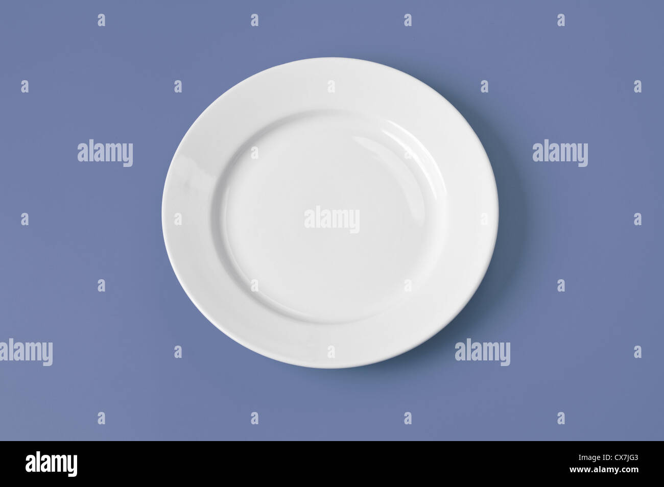 White round plate on blue background Stock Photo - Alamy