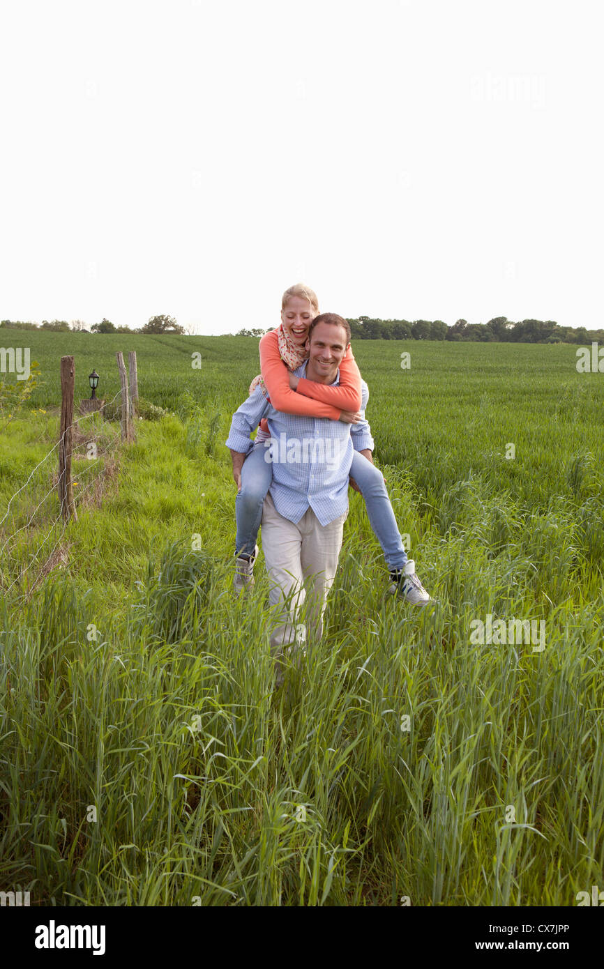A man giving his girlfriend a piggy back ride through a field Stock ...