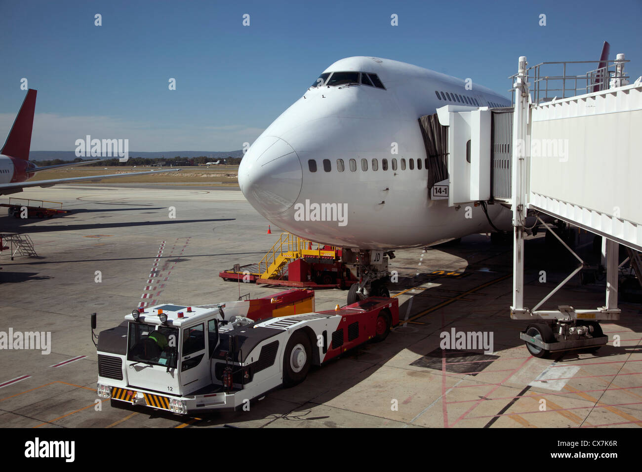 Jumbo jet attached to boarding bridge with tug in front Stock Photo - Alamy