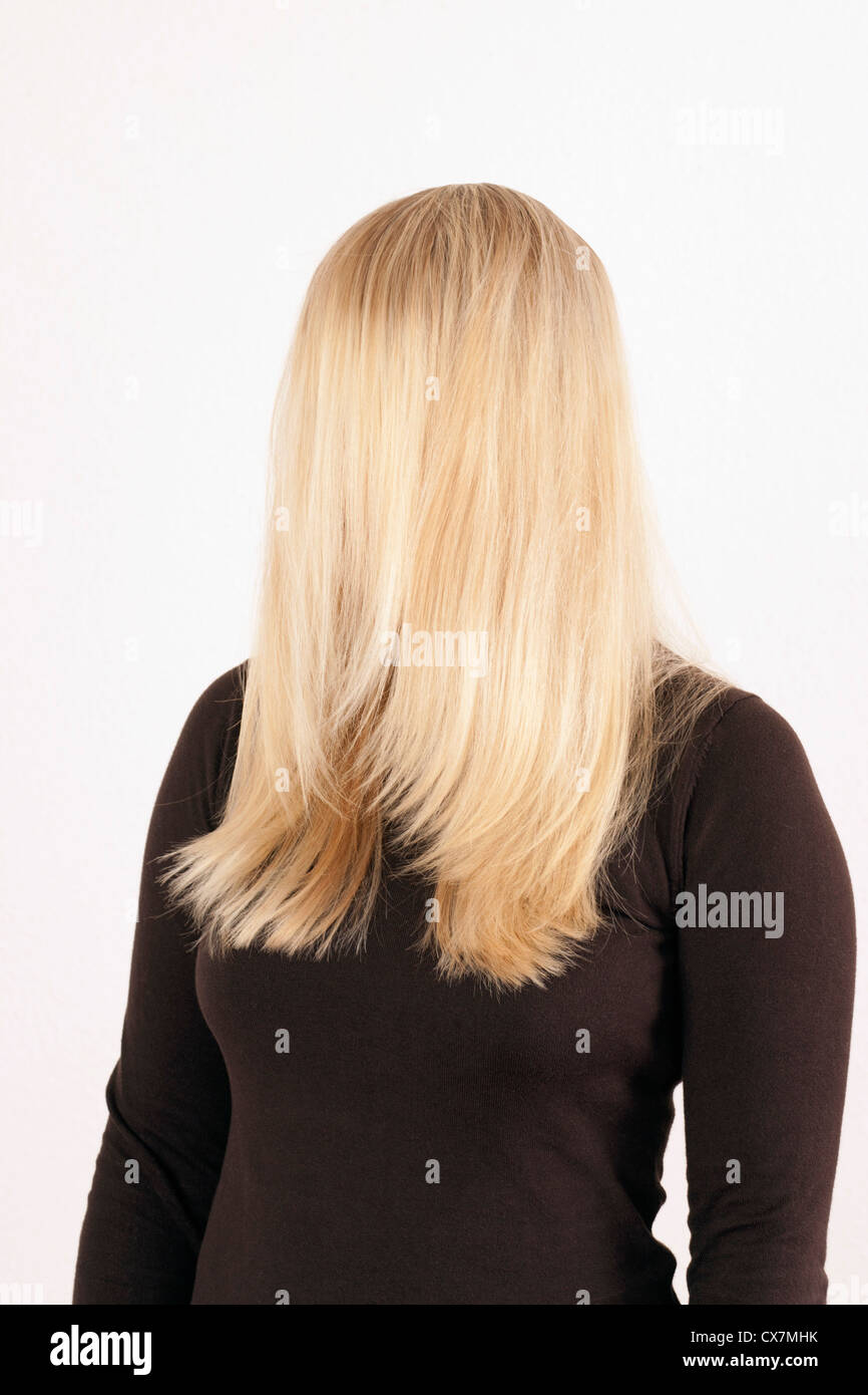 A woman standing with her long, blond hair combed forward covering her ...