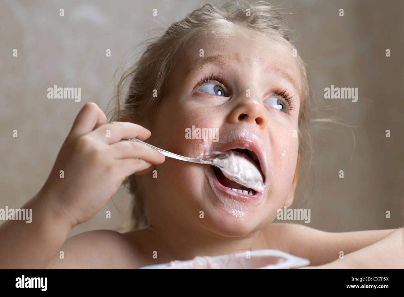A young girl making a mess out of eating yogurt Stock Photo - Alamy
