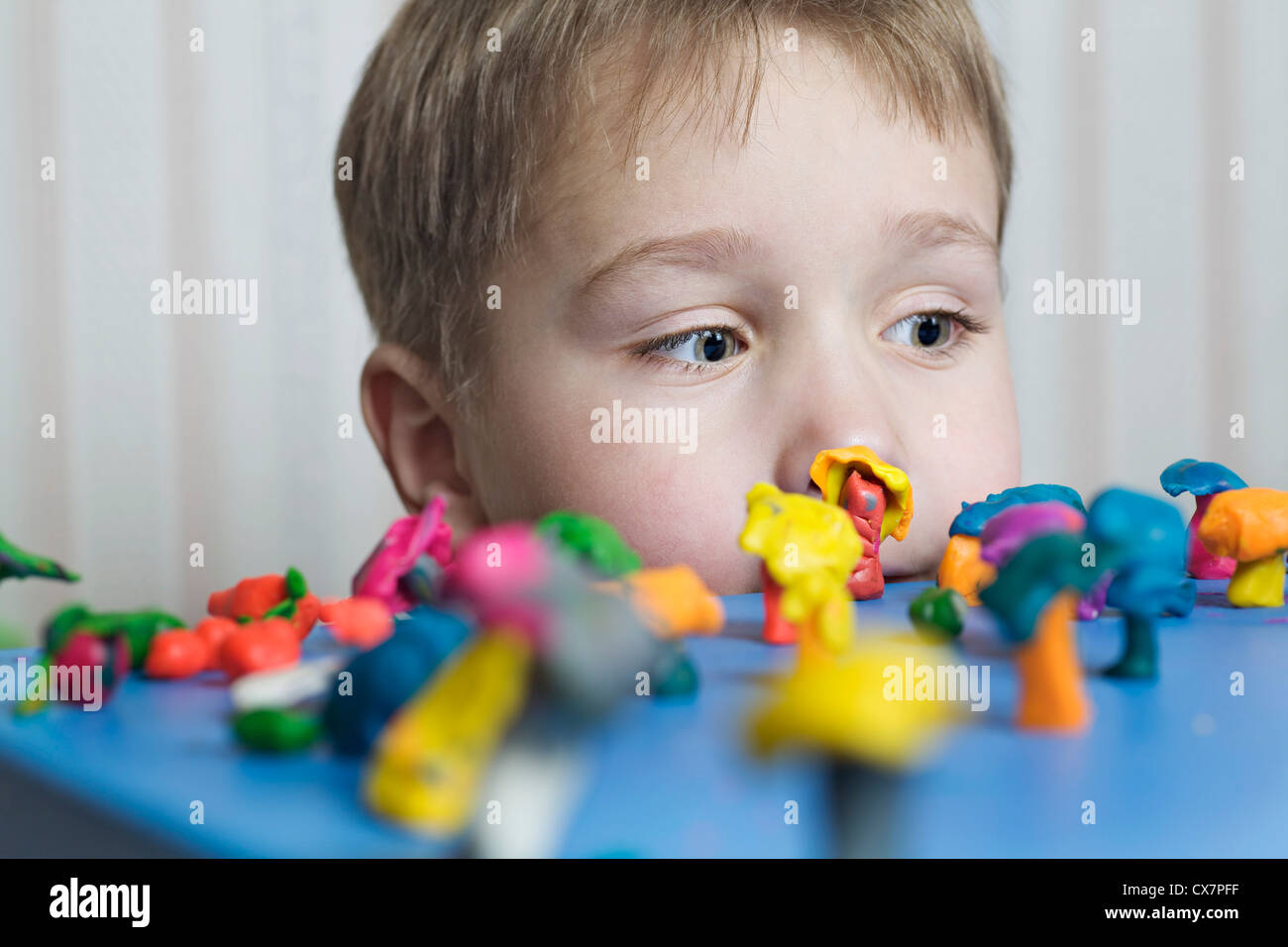 A young boy looking at various shapes made from child's play clay Stock ...