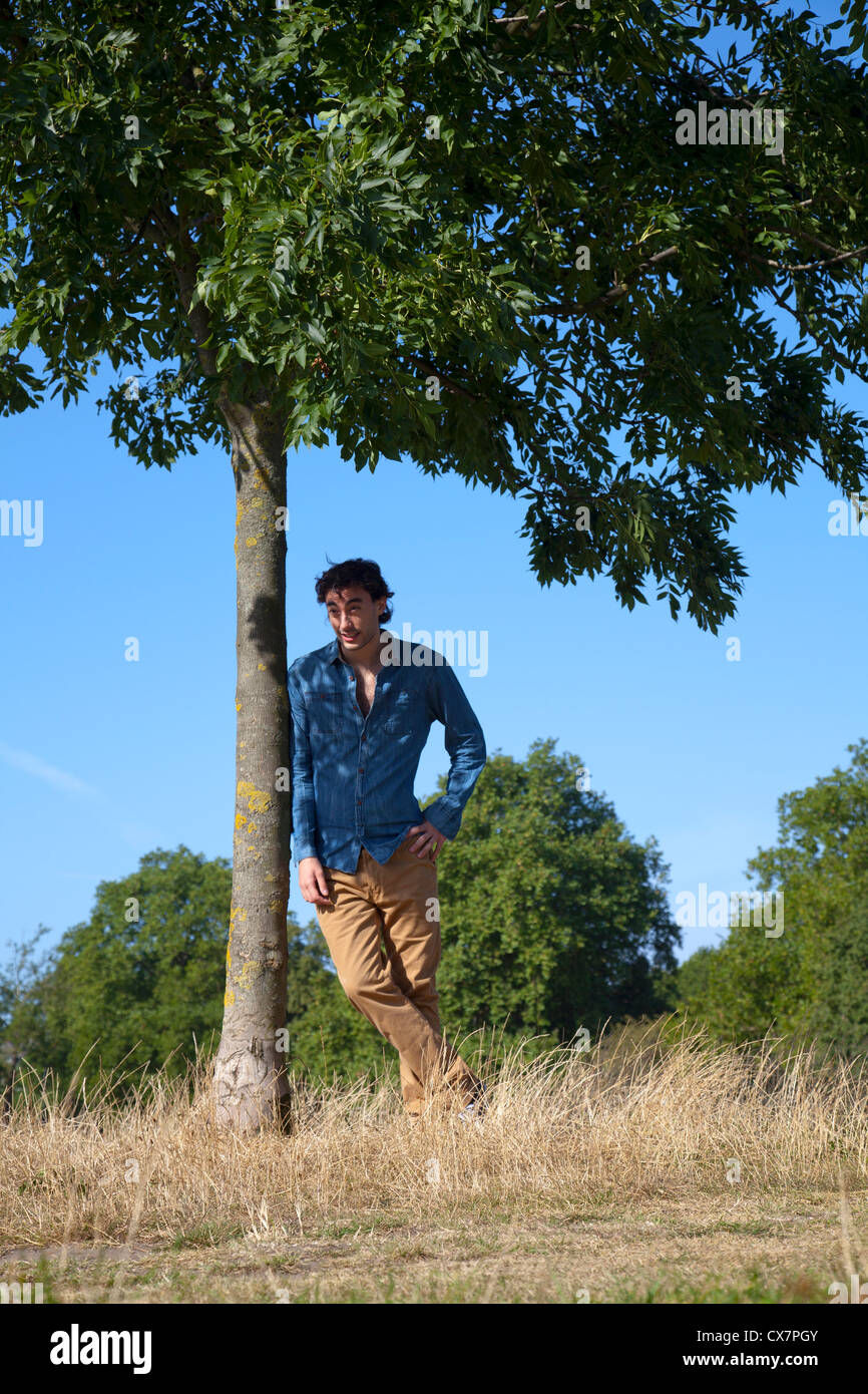 Man leaning against tree in park Stock Photo - Alamy