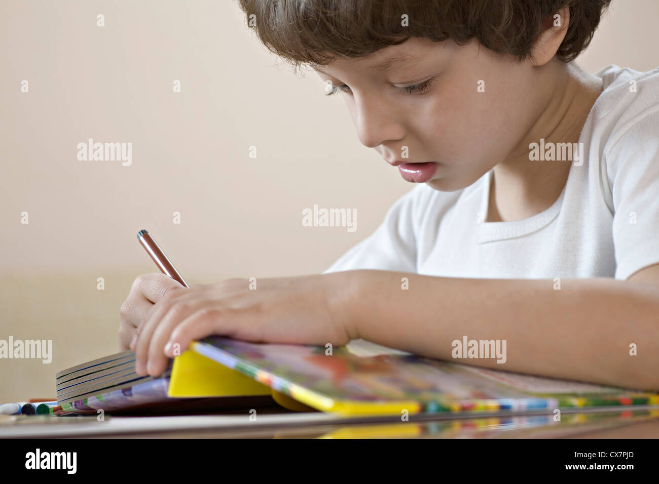 A young boy concentrating on his workbook Stock Photo - Alamy