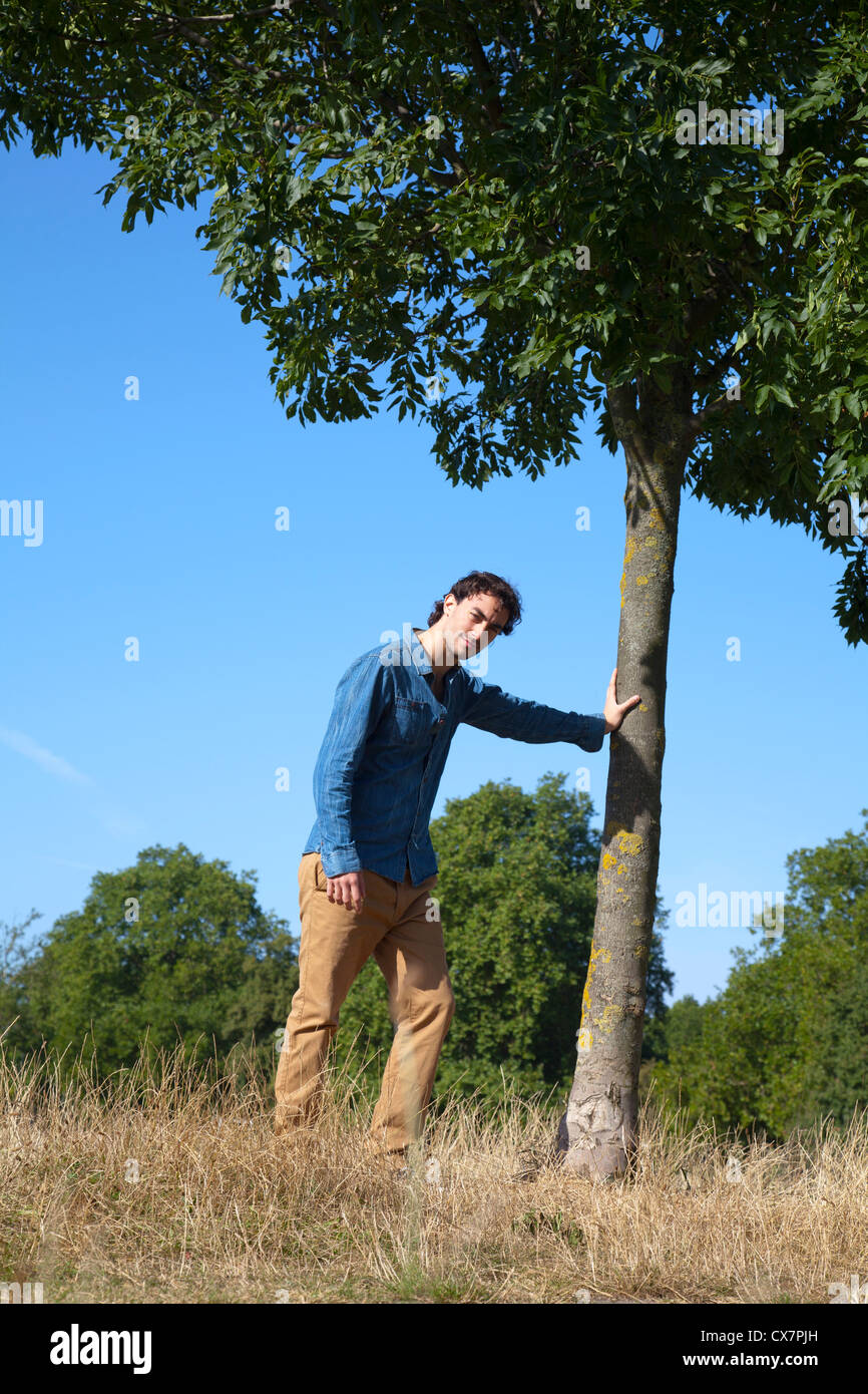 Man leaning against tree in park Stock Photo - Alamy