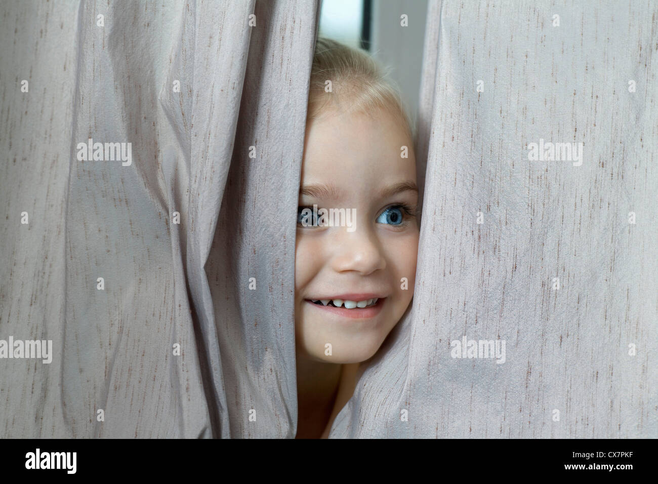A young girl hiding between window curtains Stock Photo - Alamy