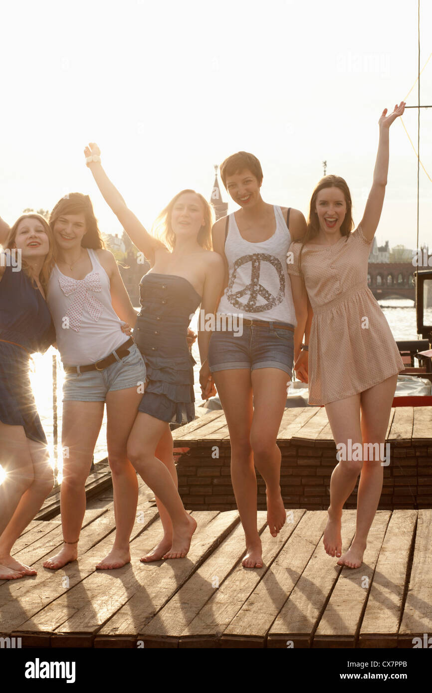 Five young female friends celebrating on a jetty, Spree River, Berlin ...