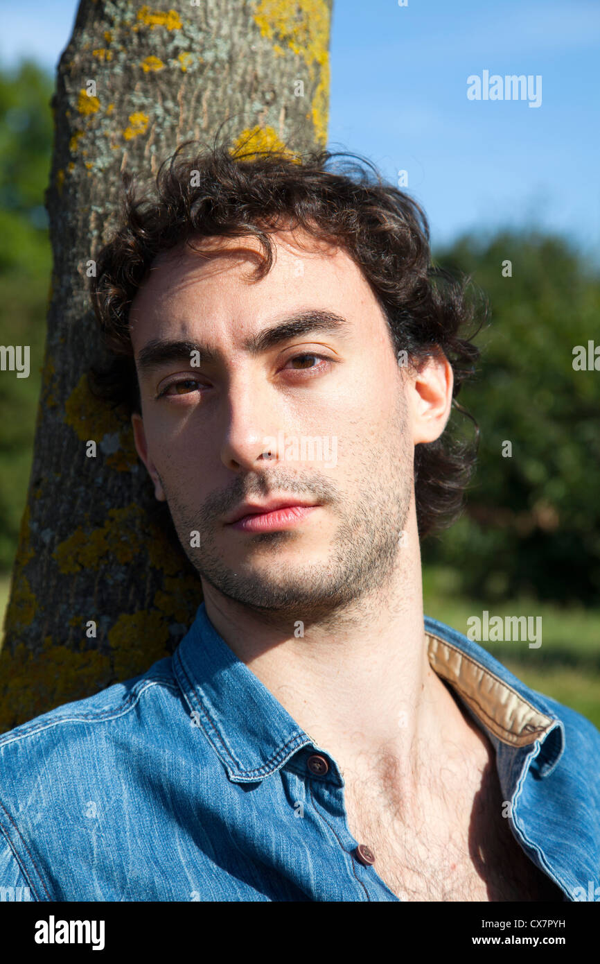 Man leaning against tree in park Portrait Stock Photo - Alamy