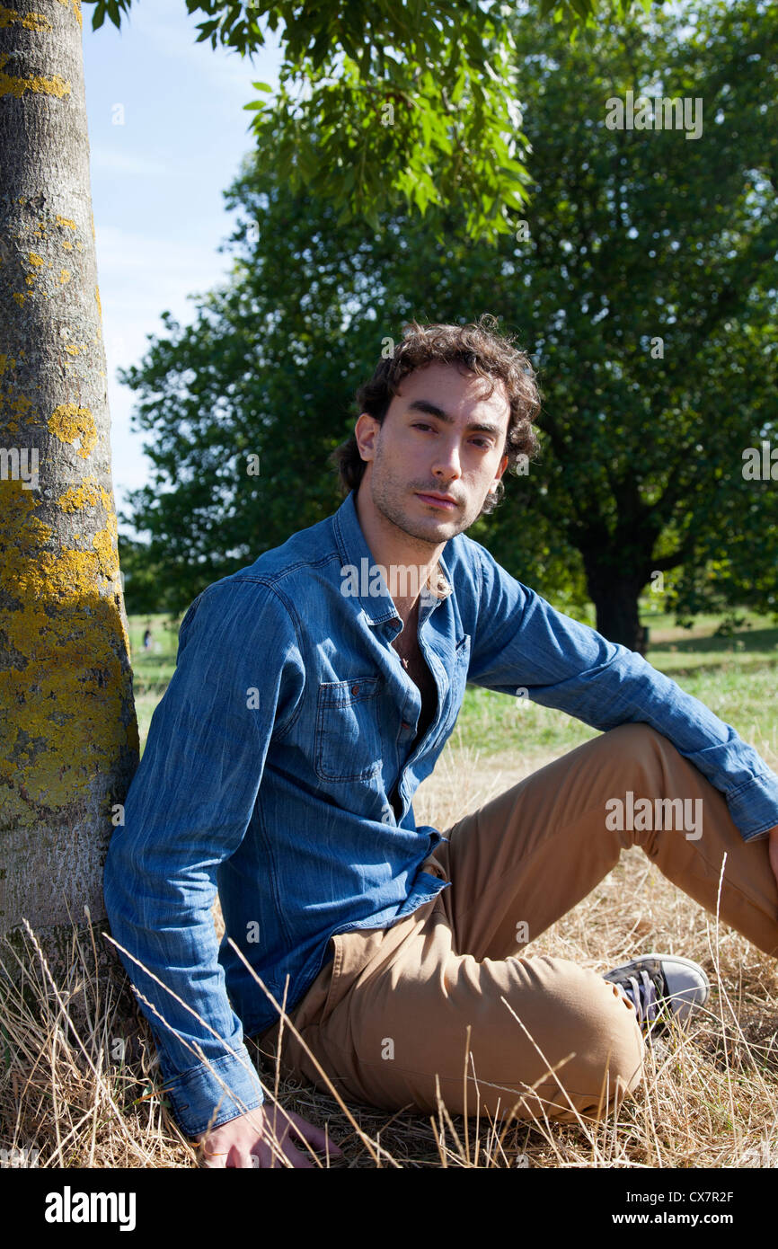 Man leaning against tree in park Stock Photo - Alamy