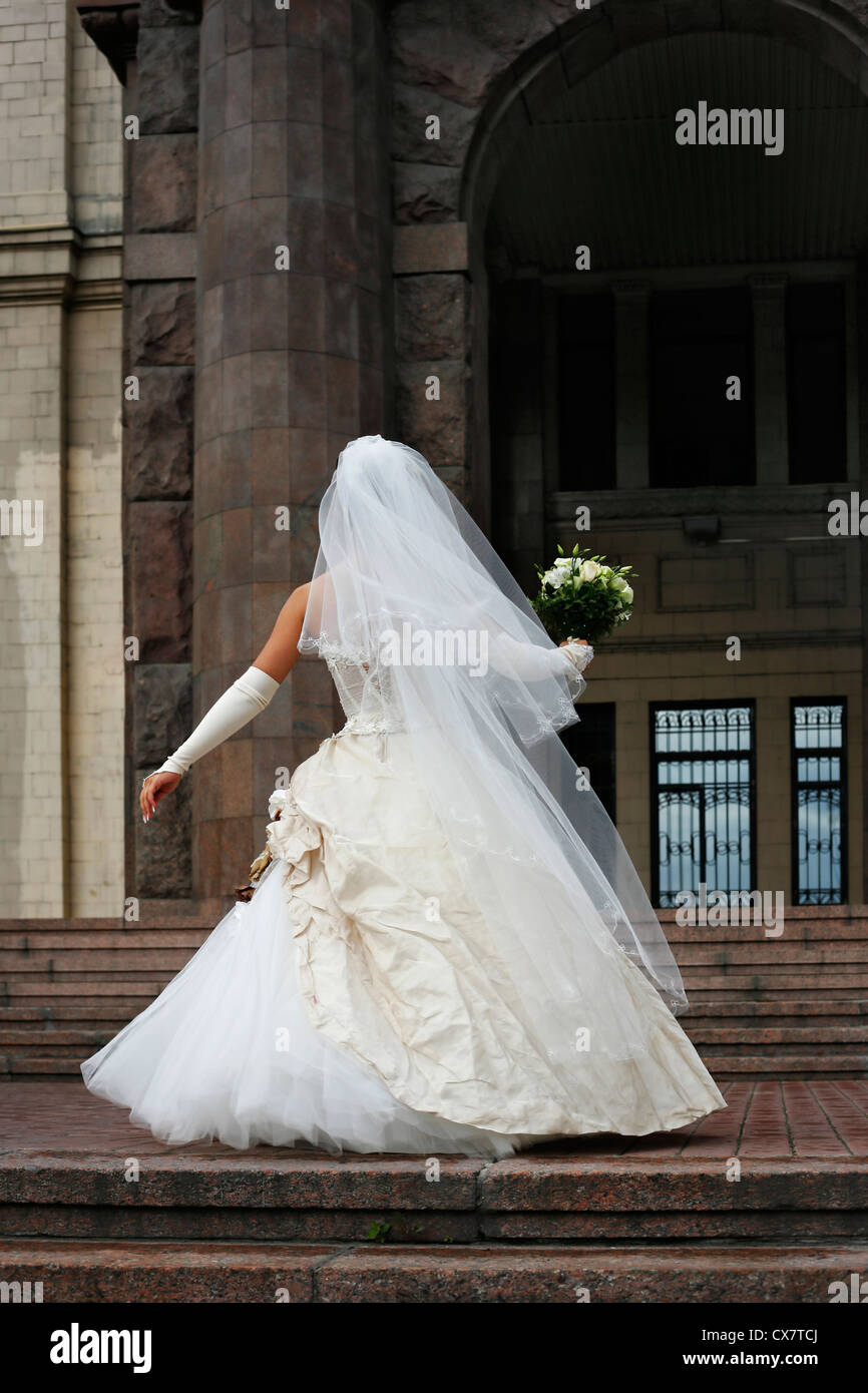 The bride with a bouquet walks upstairs Stock Photo - Alamy