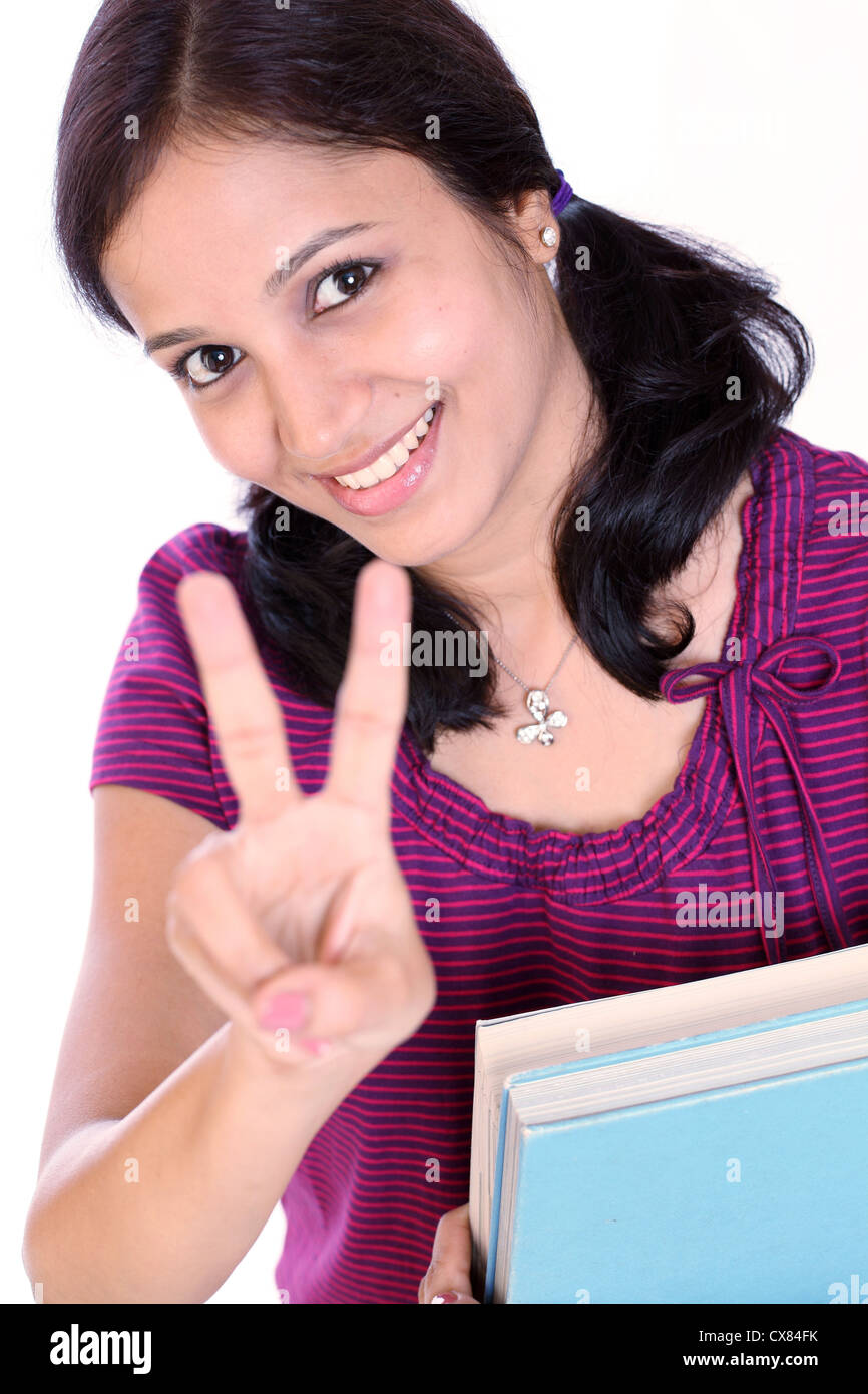 Happy young female student showing victory sign against white Stock ...